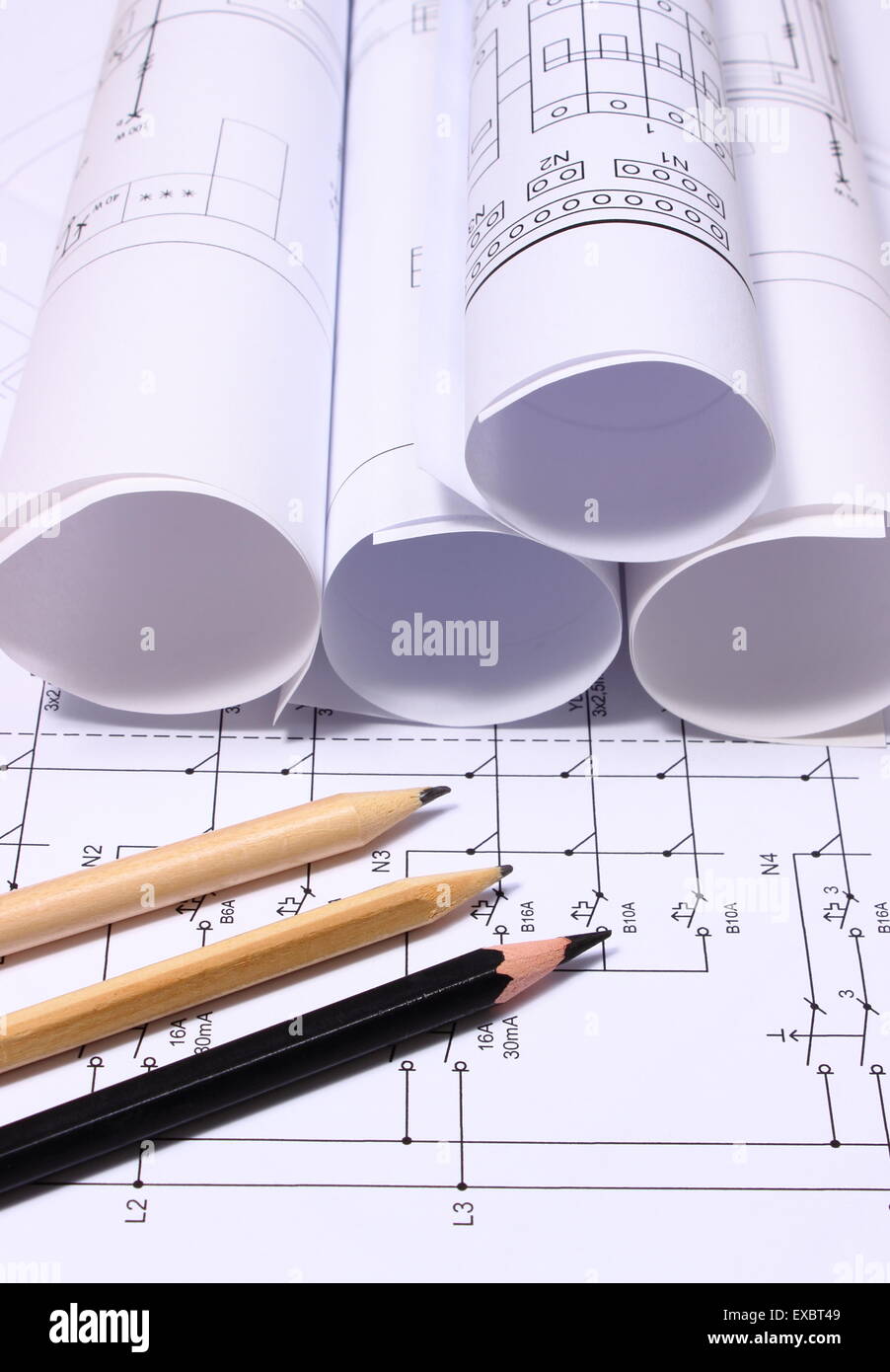 Rolls of electrical diagrams and colorful pencils on construction ...