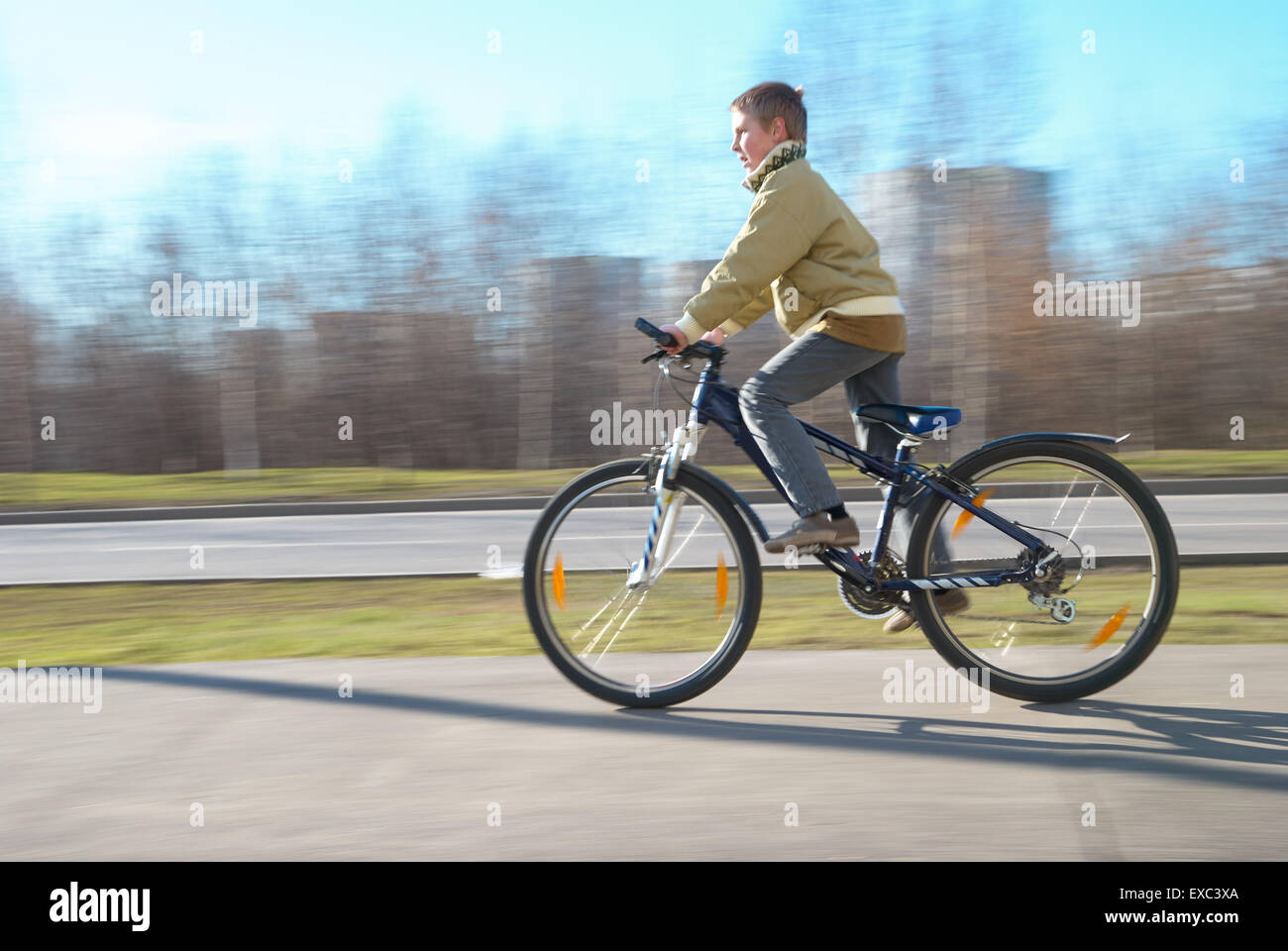 Boy speeds up on the bicycle path riding his bike Stock Photo - Alamy