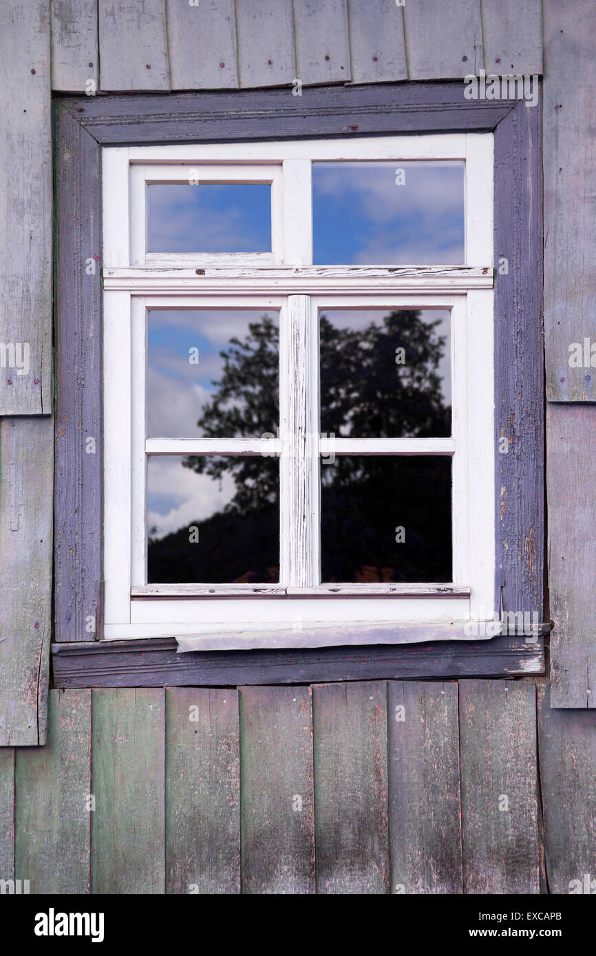 window of an old wooden house with the reflection of a tree in the ...