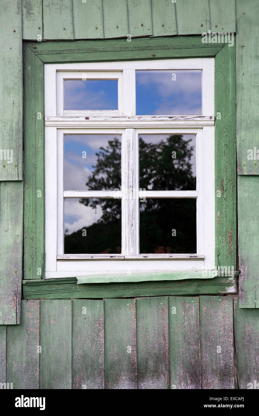 window of an old wooden house with the reflection of a tree in the ...