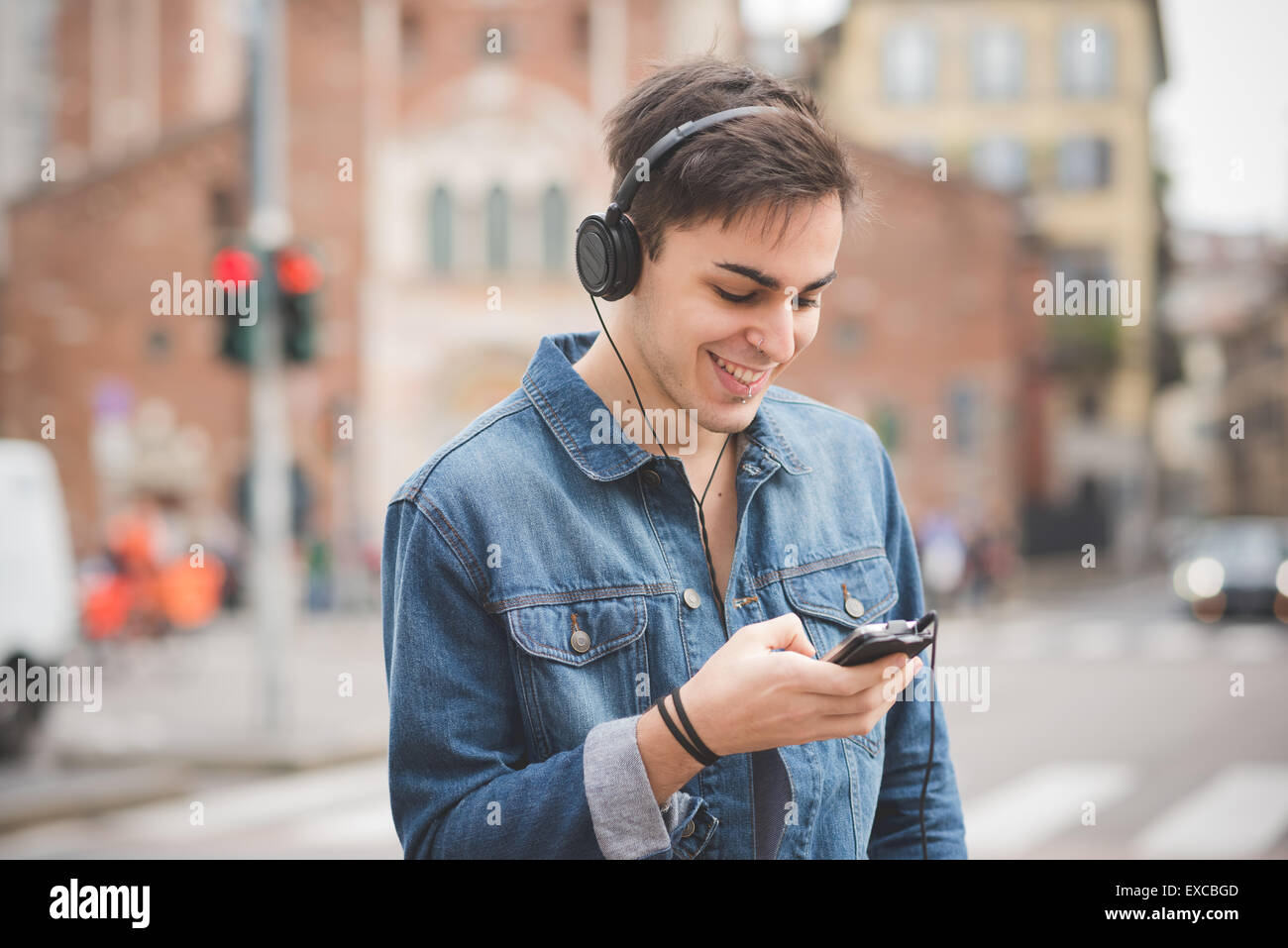young handsome alternative dark model man in town listening to music ...