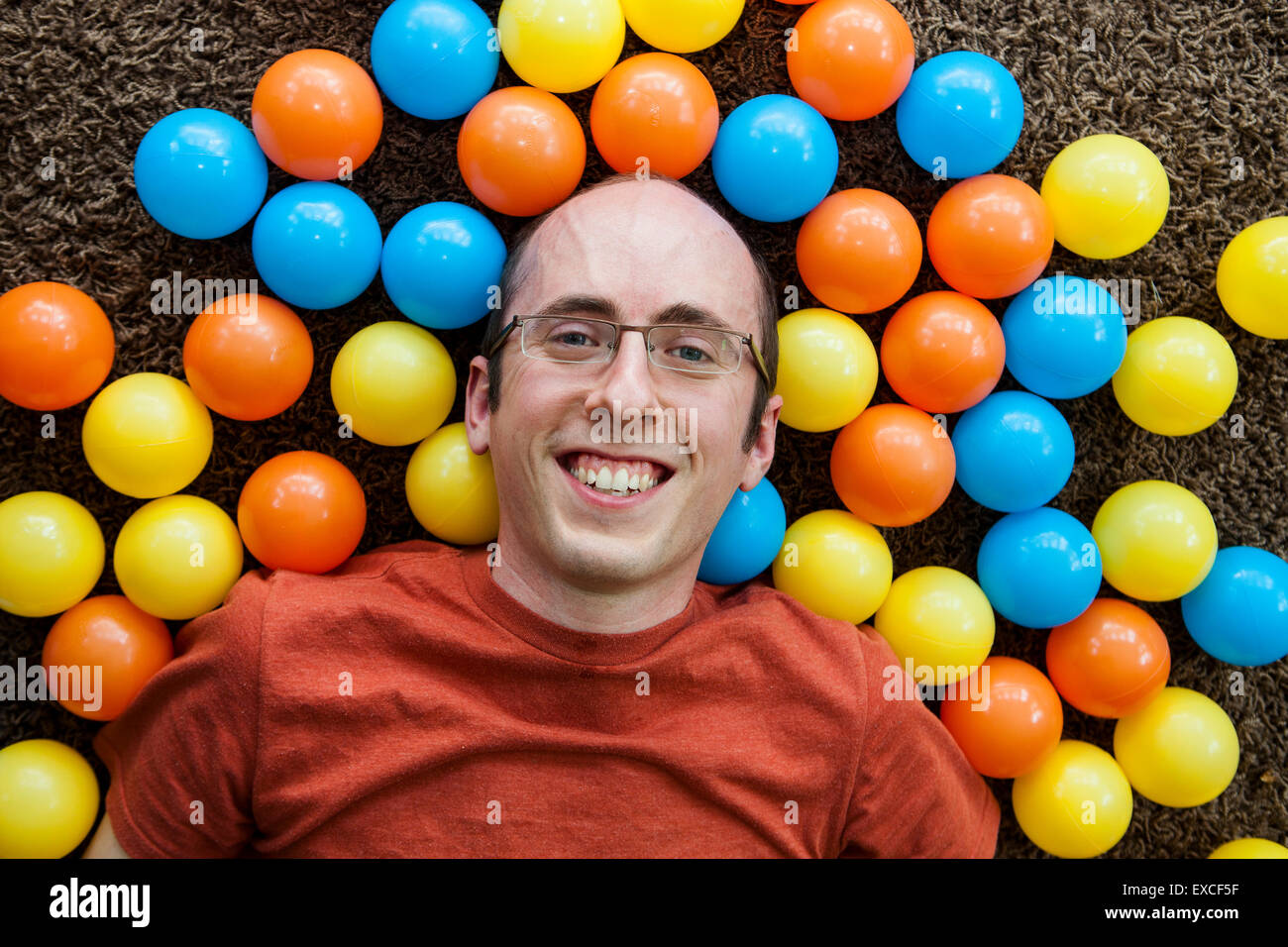 A man lays on the the floor smiling and surrounded by a pile of ...
