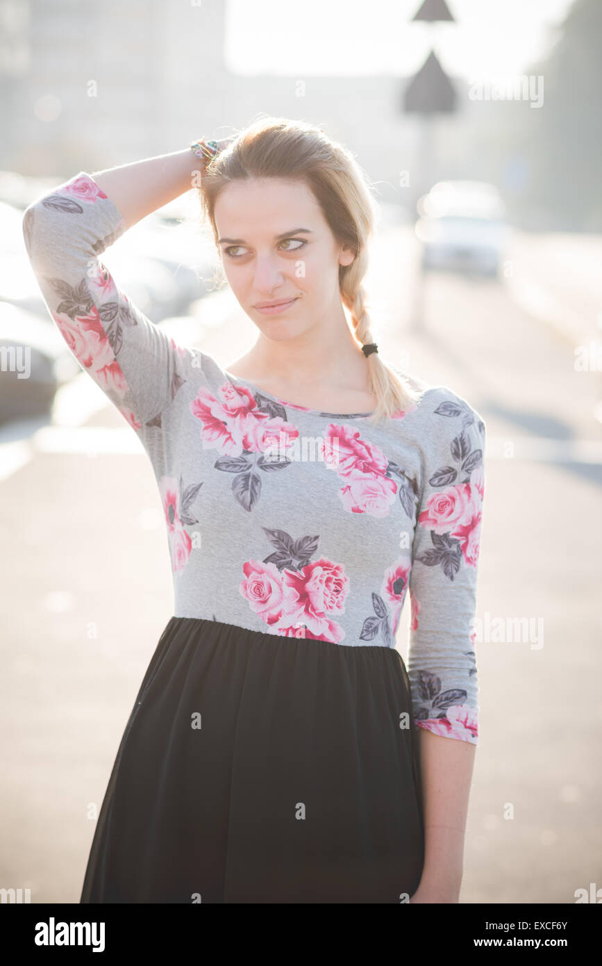 Young And Beautiful Blonde Caucasian Girl Walking Through The City At Dusk Wearing A Floral