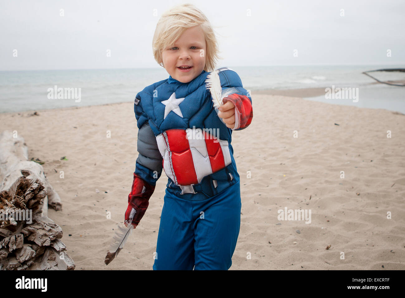 A four year old boy wearing a Captain America costume holds up two bird ...
