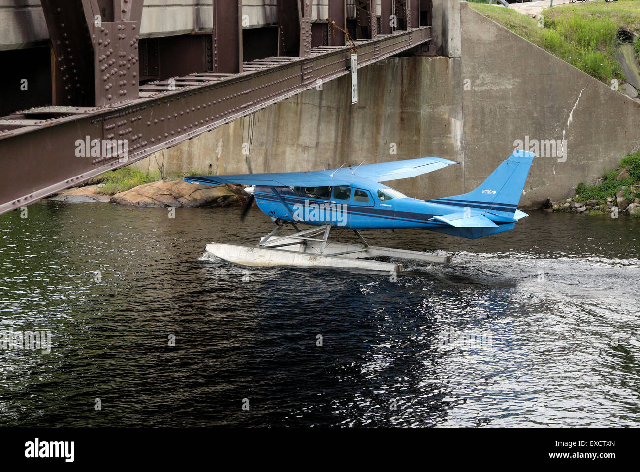 Cessna float plane seaplane taxing under a bridge at Long Lake New York ...