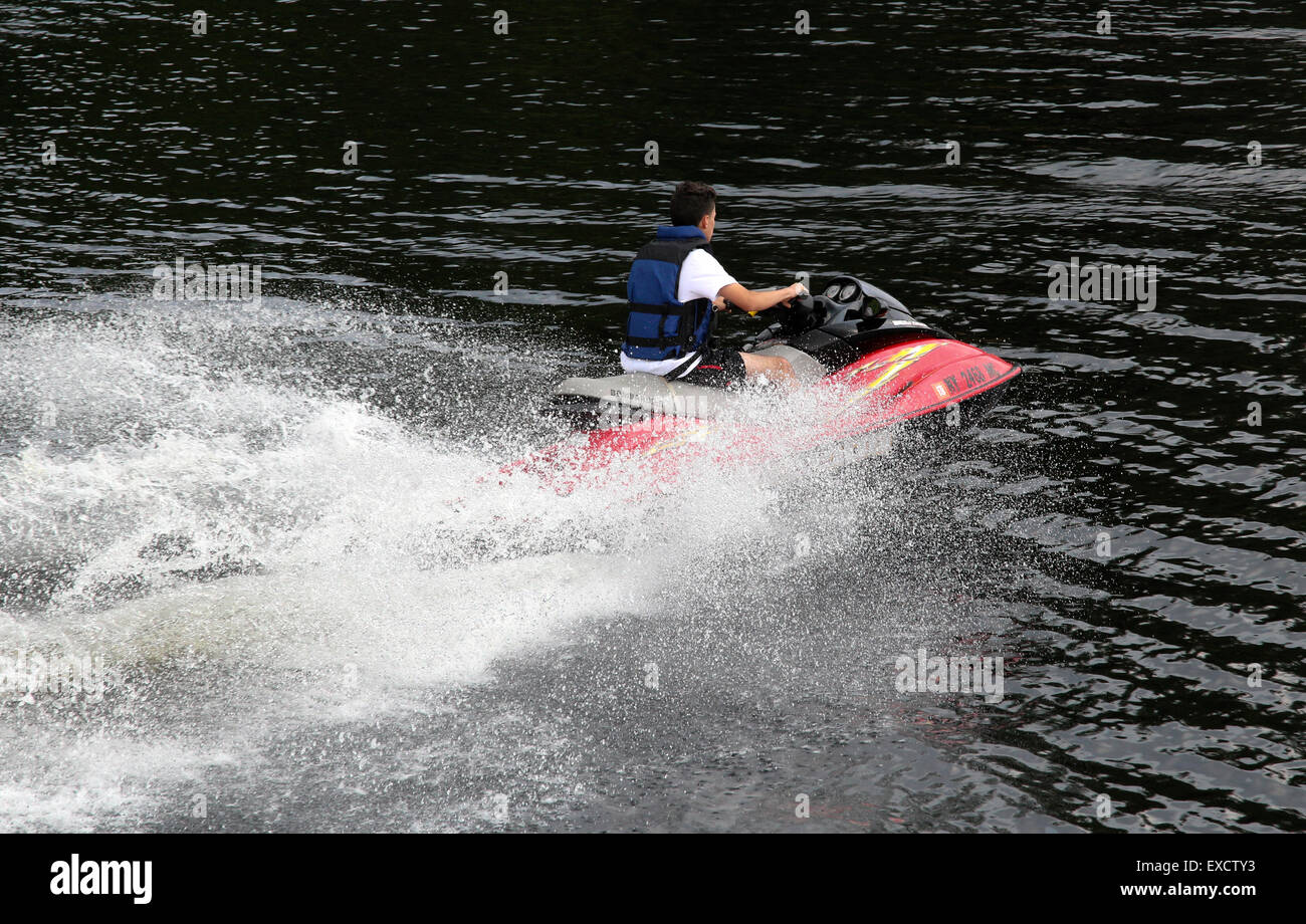 Teenage boy riding a red Sea Doo Bombardier personal watercraft. Long ...