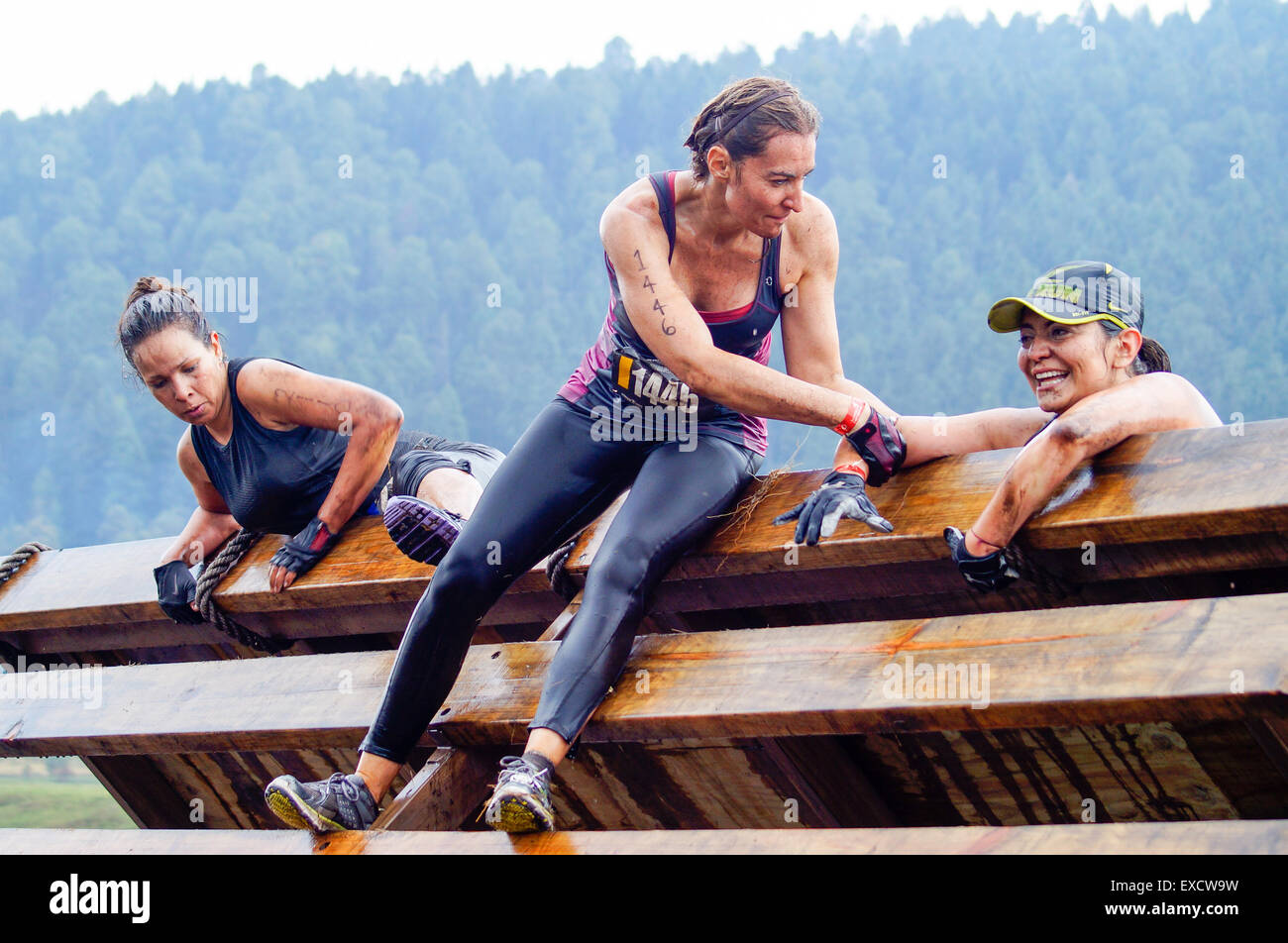 Three female athletes climbing a wooden ramp on a hell run Stock Photo ...