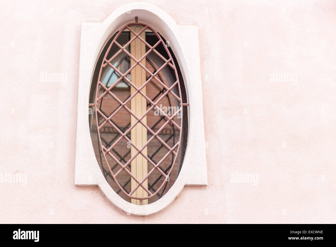 Iron grating round window with beige wooden frame Stock Photo - Alamy