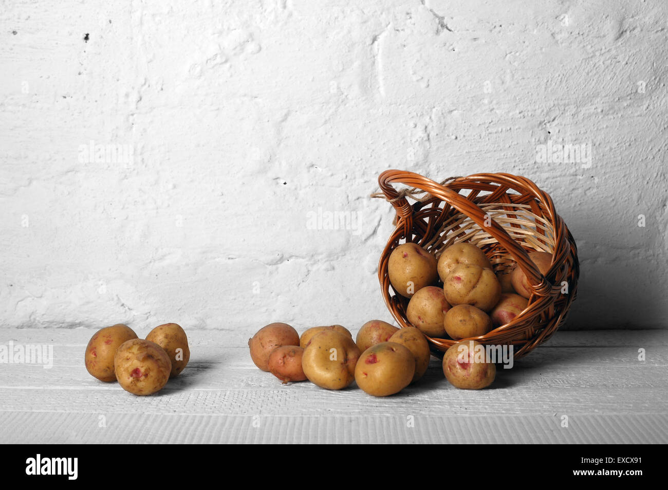 Basket with potatoes on old white planks a background Stock Photo - Alamy