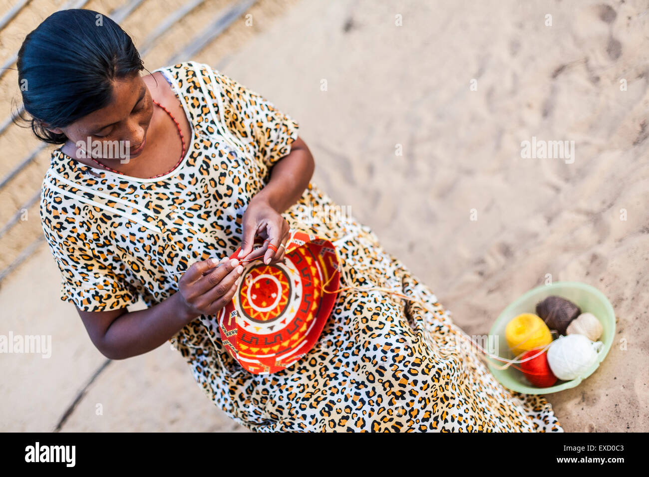 A young Wayuu indigenous woman knitting a "mochila", or traditional ...