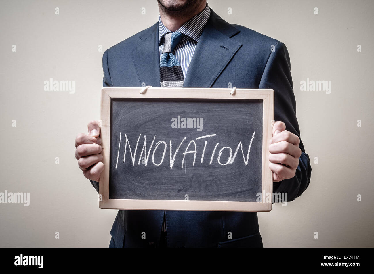 businessman holding blackboard written innovation on gray background ...