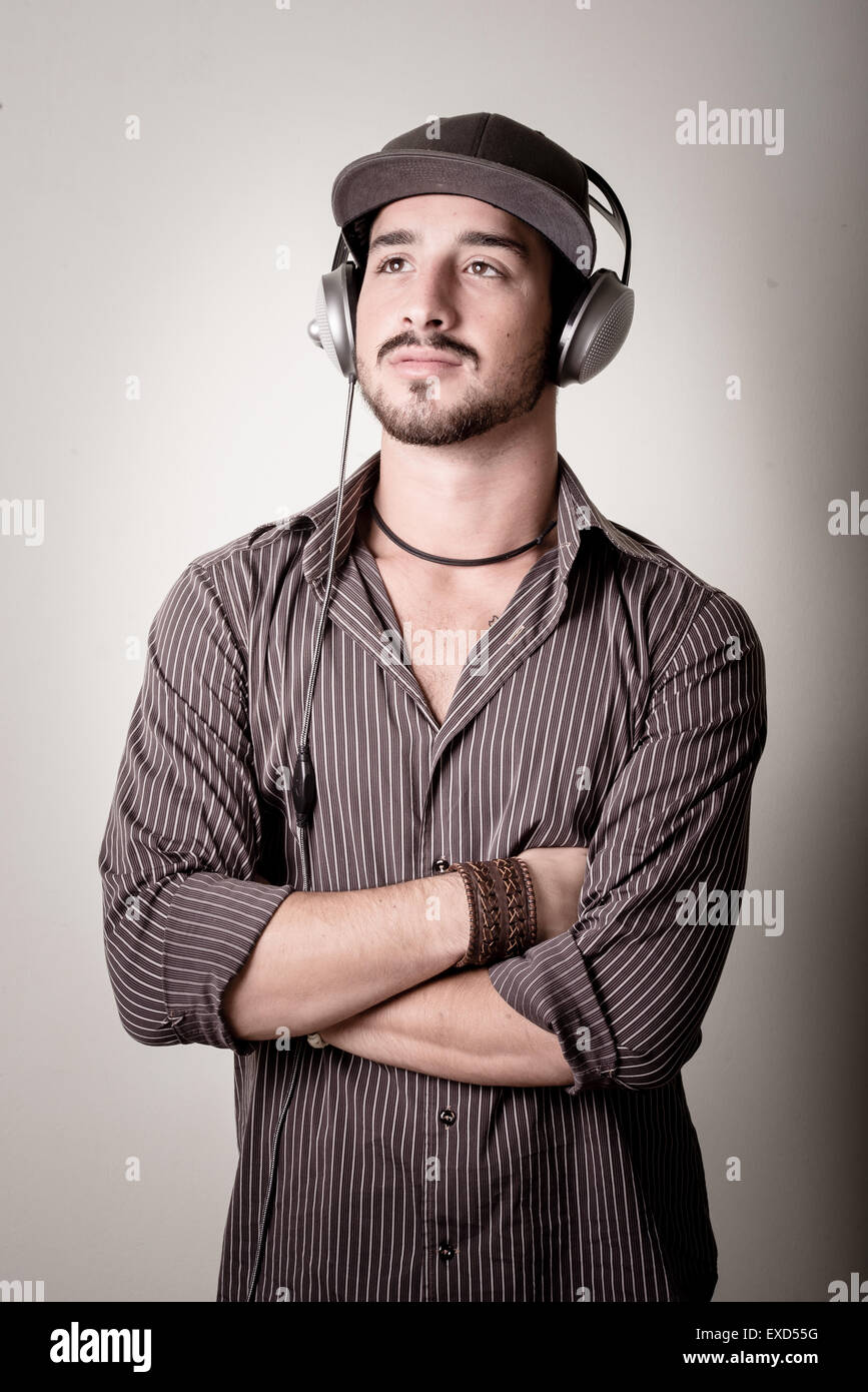 young stylish man listening to music on gray background Stock Photo - Alamy