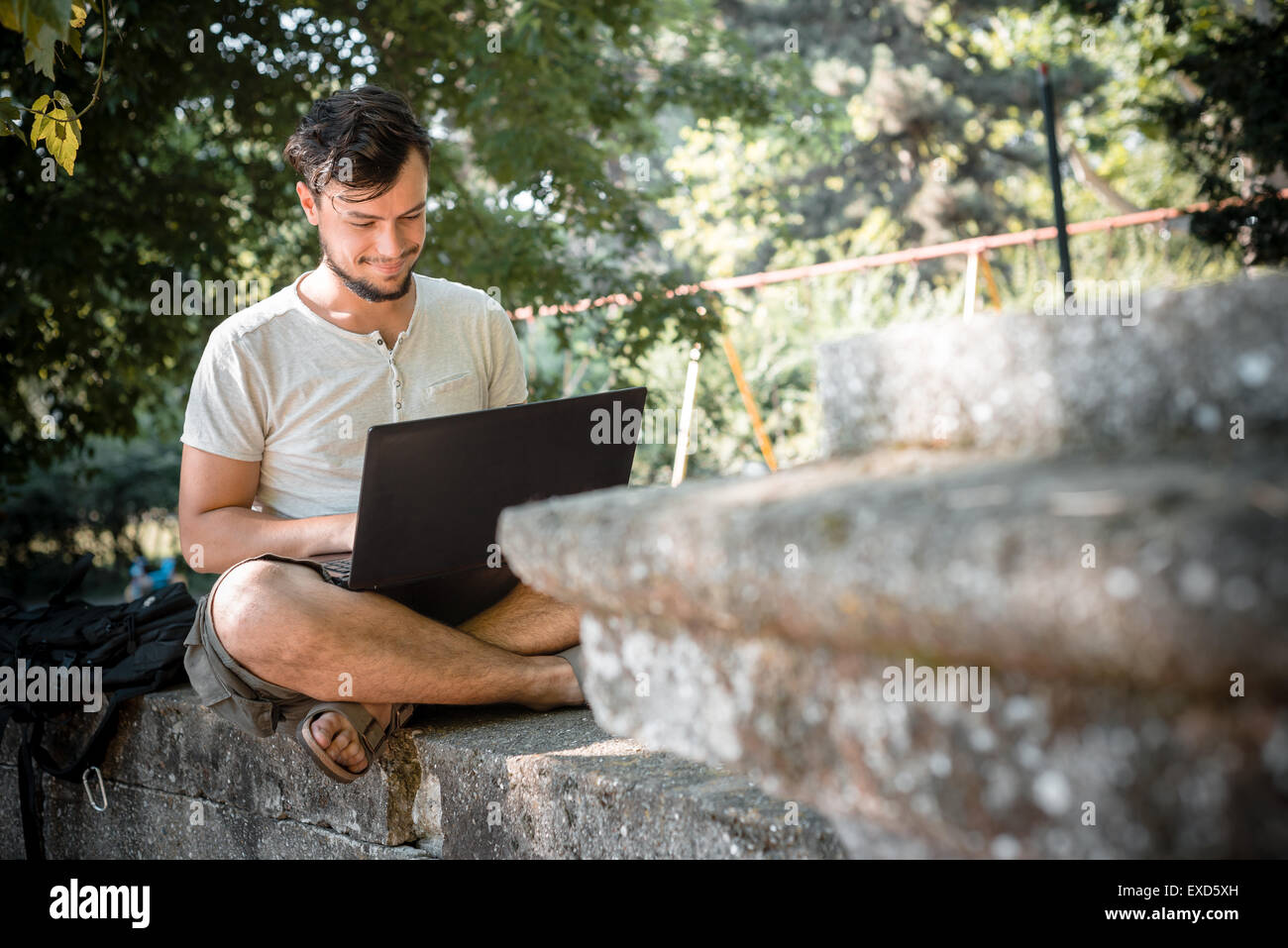young stylish man using notebook at the park Stock Photo - Alamy