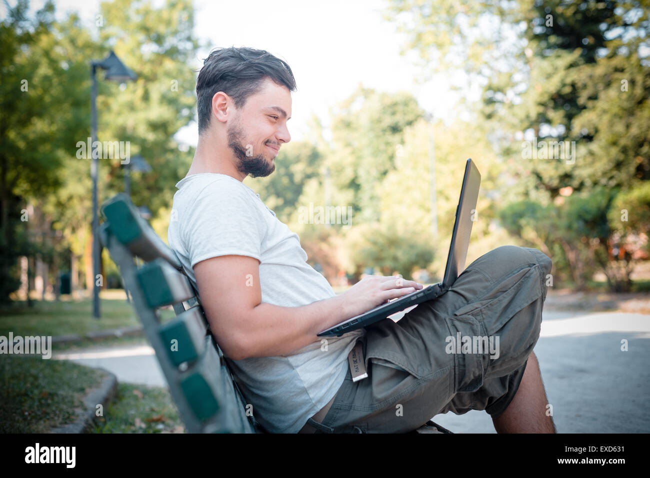 young stylish man using notebook at the park Stock Photo - Alamy