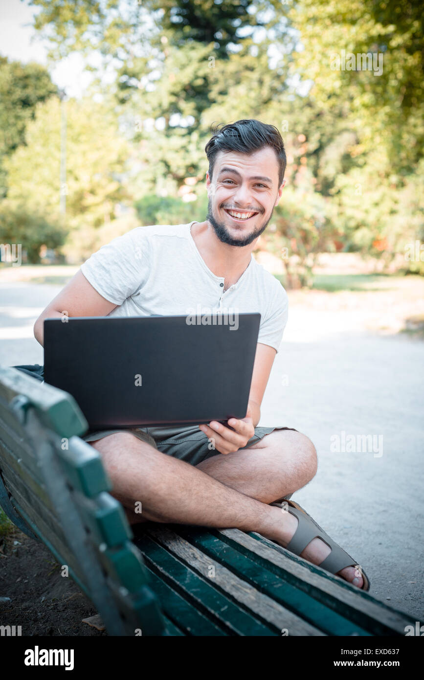 young stylish man using notebook at the park Stock Photo - Alamy