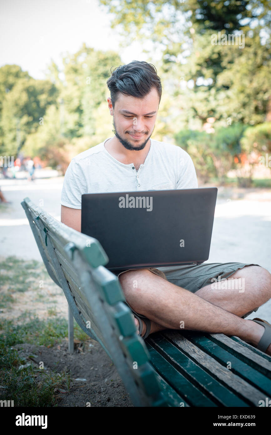 young stylish man using notebook at the park Stock Photo - Alamy