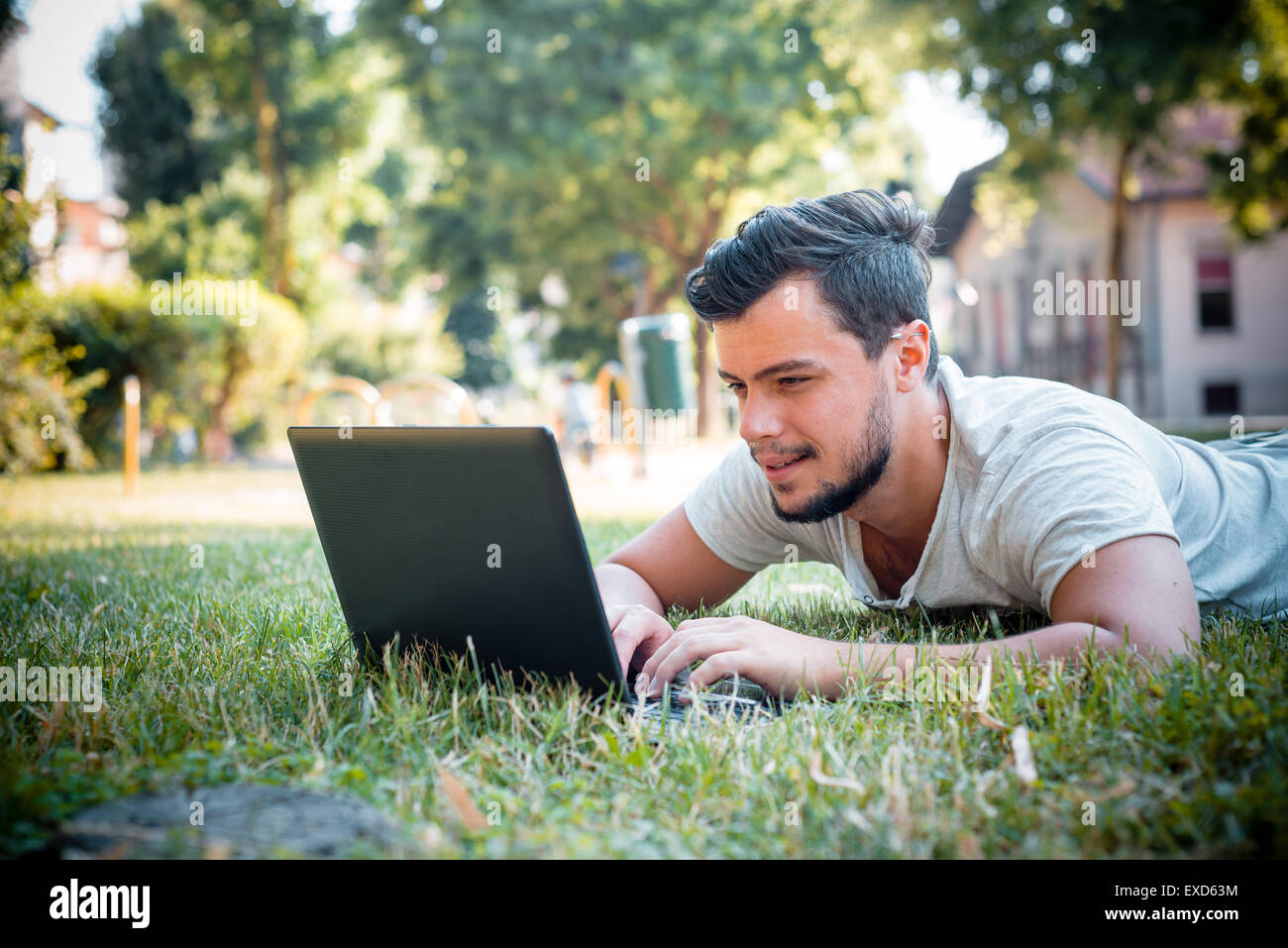 young stylish man using notebook at the park Stock Photo - Alamy