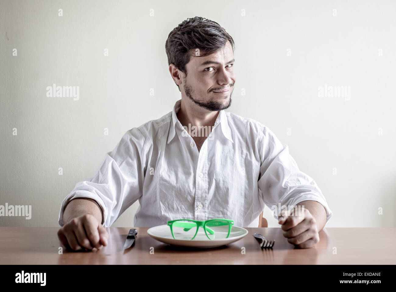 young stylish man with white shirt eating green eyeglasses behind a ...
