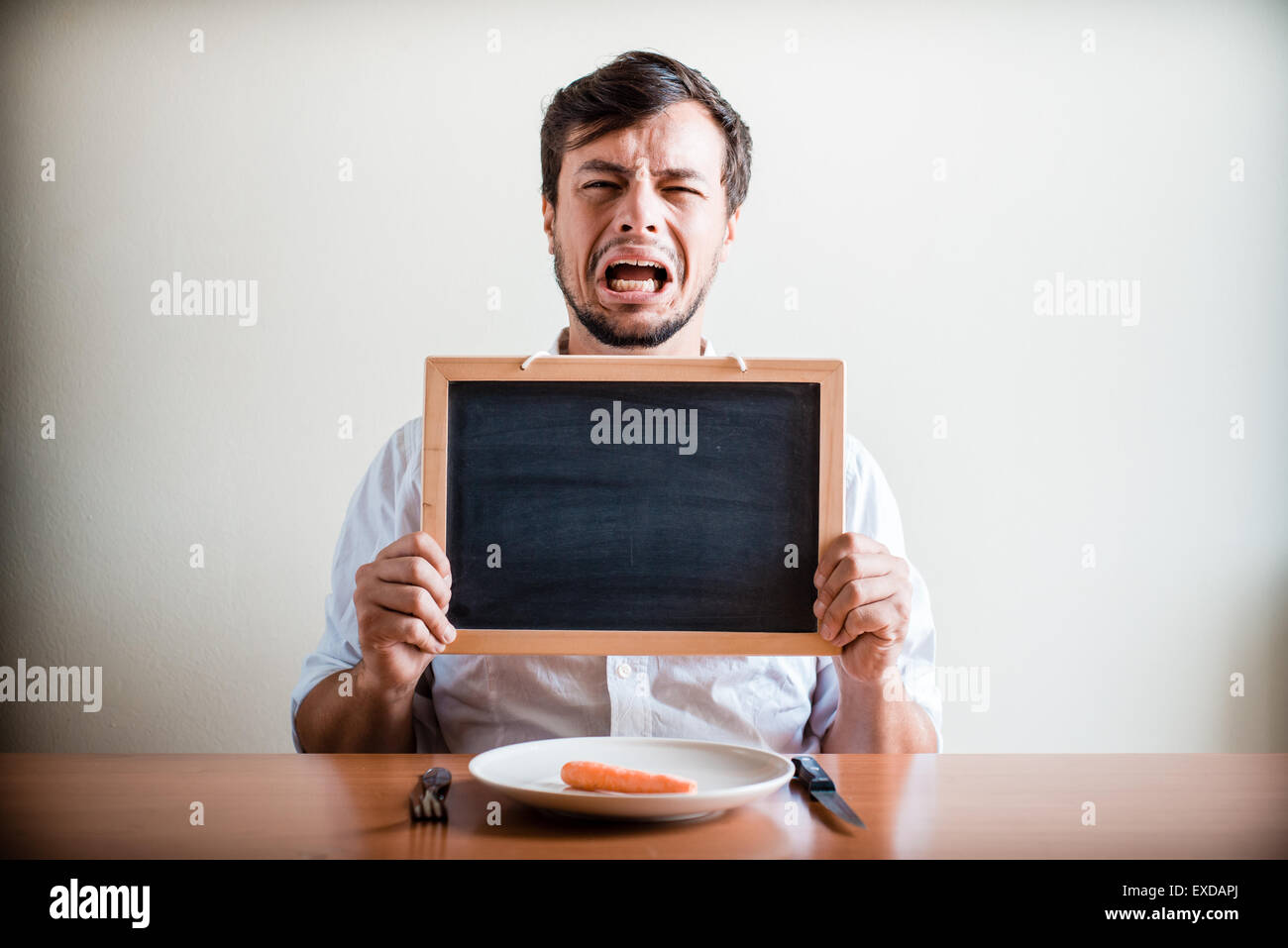 young stylish man with white shirt holding blackboard behind a table ...