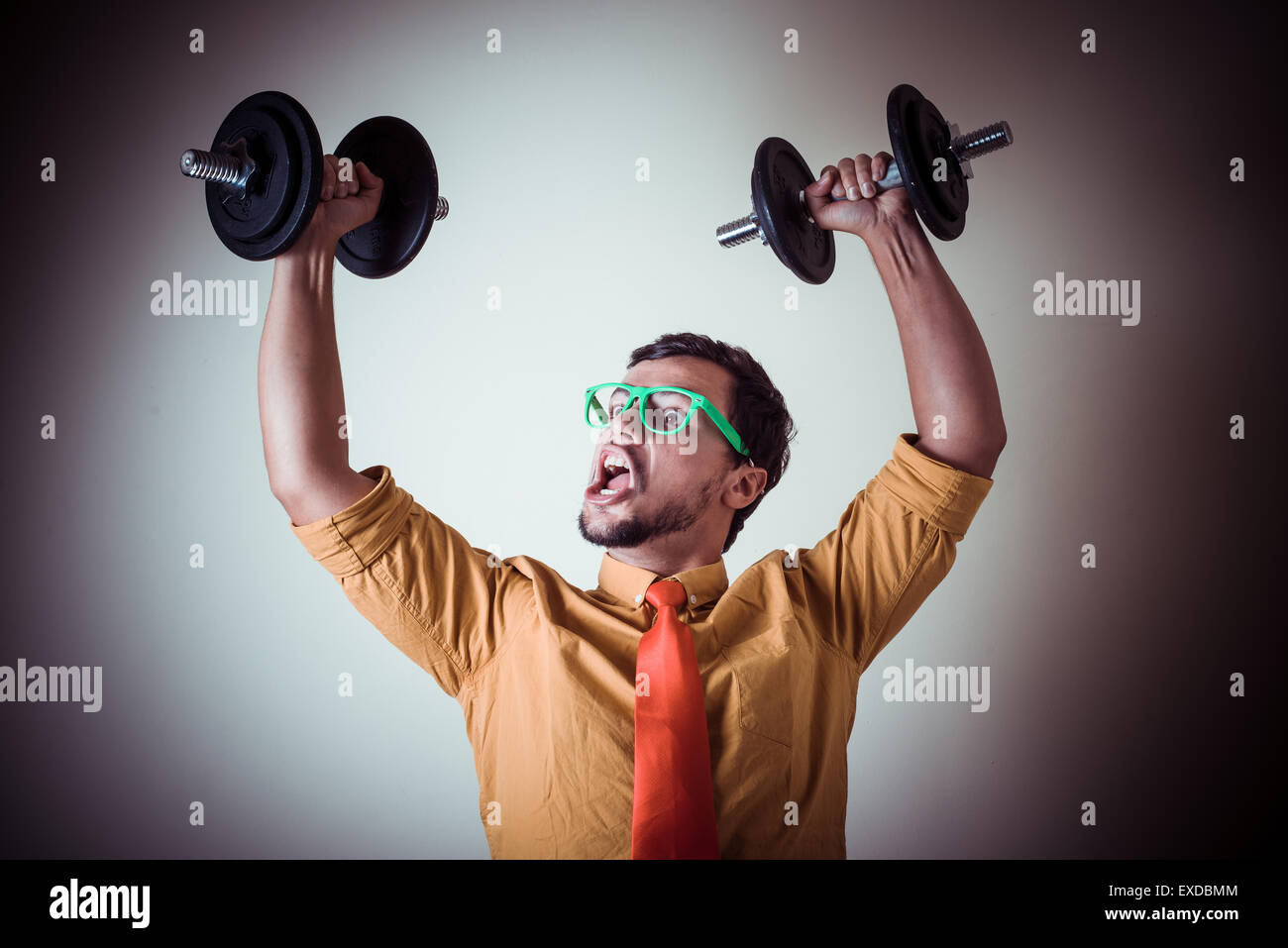 funny crazy young man weightlifting on gray background Stock Photo - Alamy