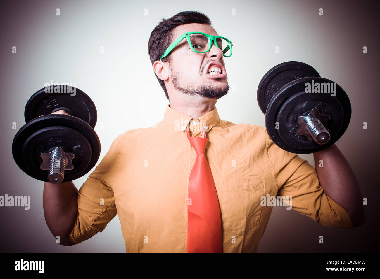 funny crazy young man weightlifting on gray background Stock Photo - Alamy