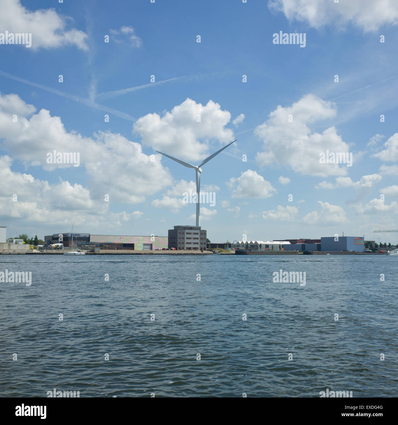 A modern windmill Dutch wind turbine towers above buildings at the side ...