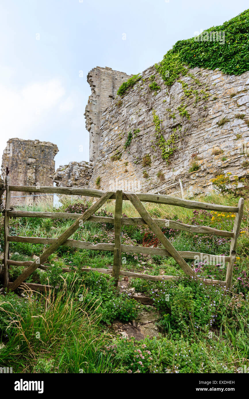 Partly closed old weathered wooden farm gate across track past ruined ...
