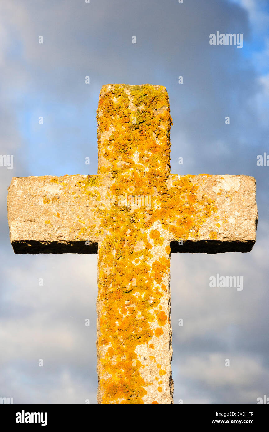Sunlit old stone Christian cross in the churchyard at the English ...