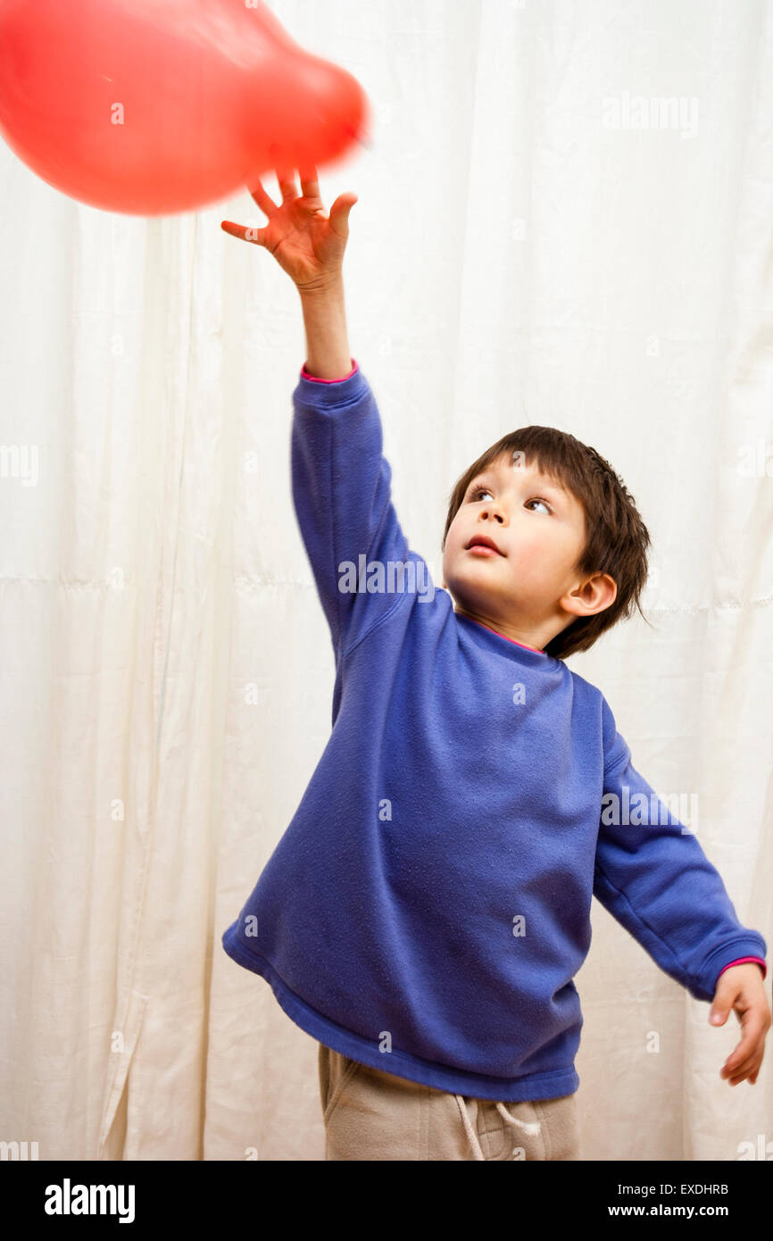 Caucasian child, boy, playing indoors with colored balloons. 6-7 year ...
