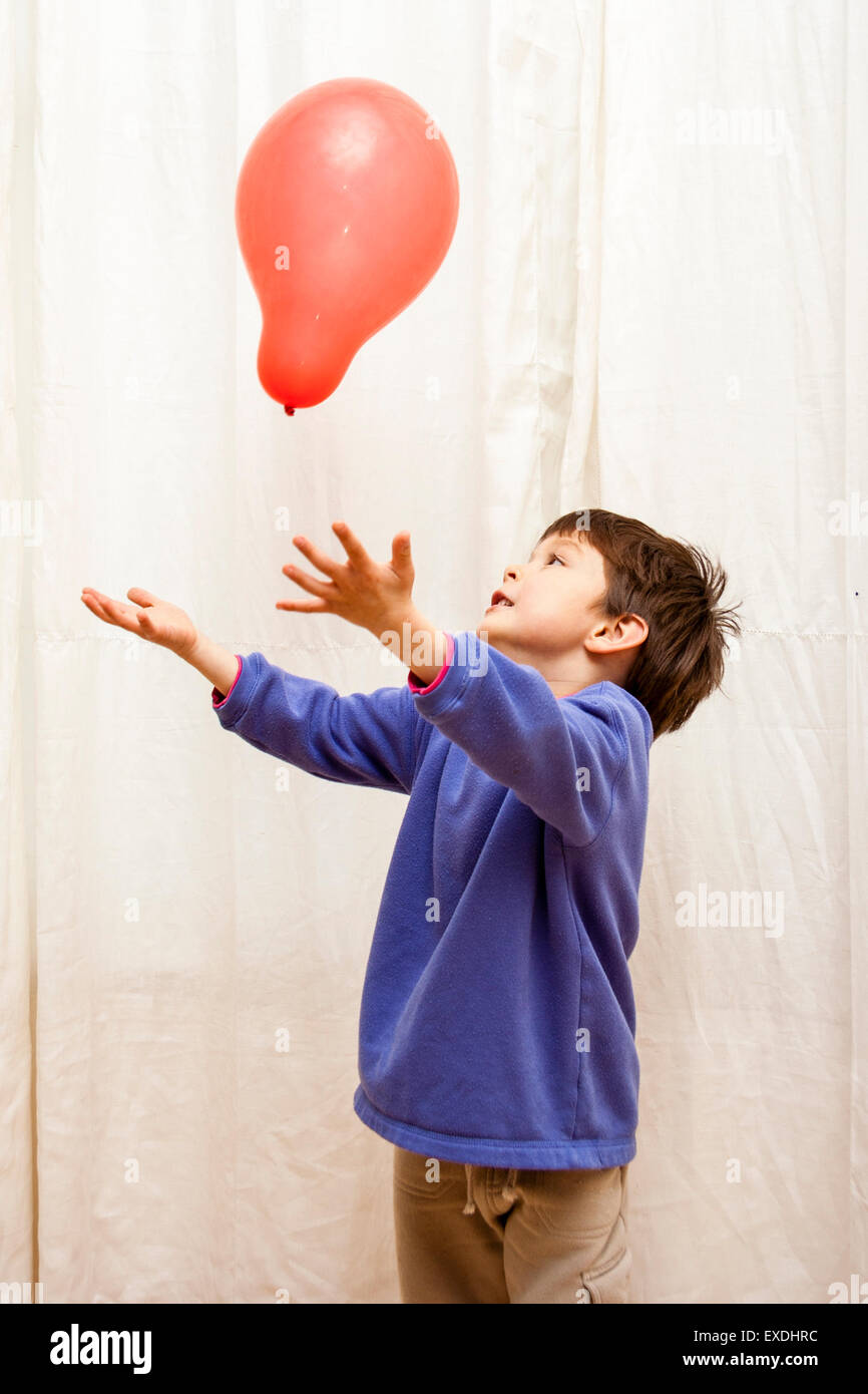 Caucasian child, boy, playing indoors with colored balloons. 6-7 year ...