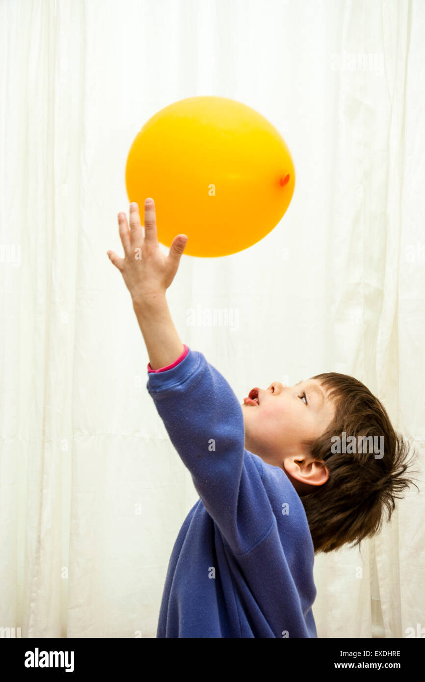 Caucasian child, boy, playing indoors with colored balloons. 6-7 year ...