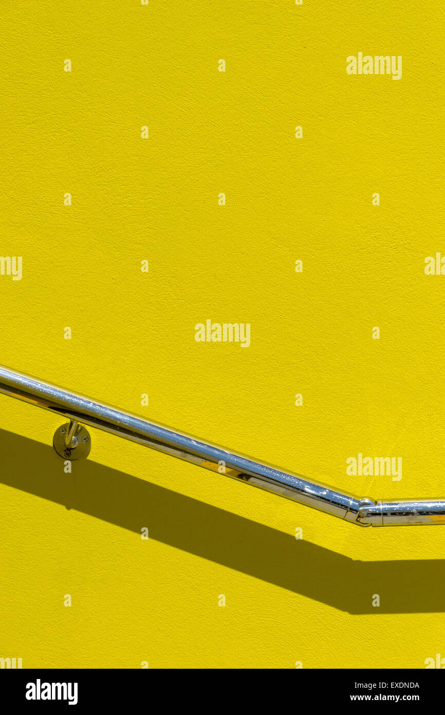 A chrome steel rail against a yellow painted wall Stock Photo - Alamy