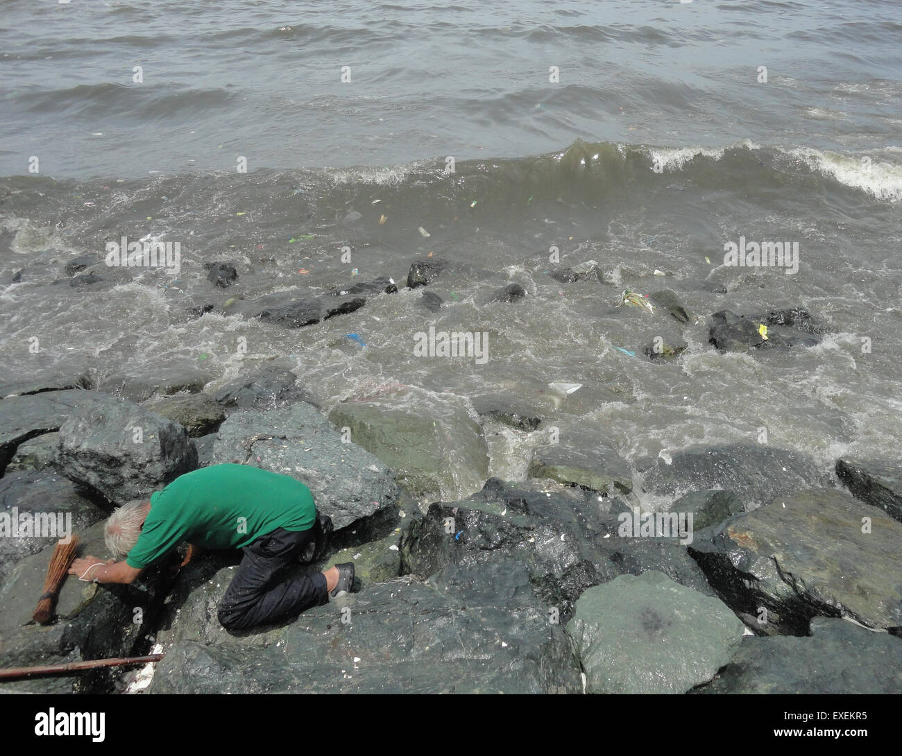 Manila, Philippines. 13th July, 2015. A Filipino cleans the rocky ...