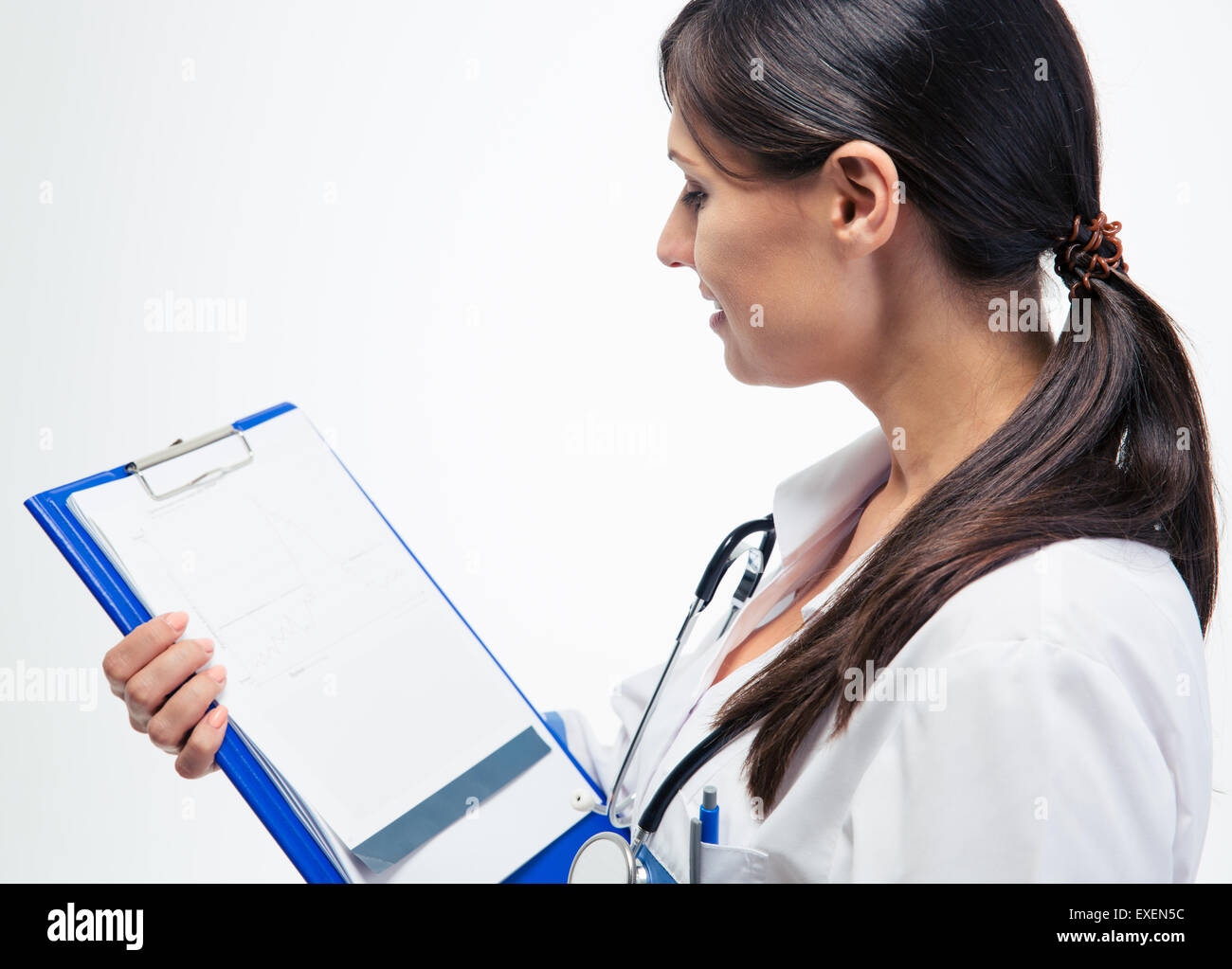 Portrait of a beautiful female doctor reading notes on clipboard ...