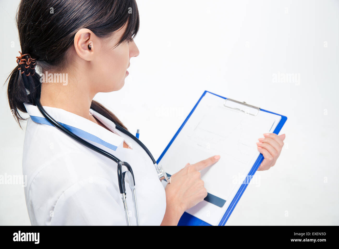 Portrait of a young medical doctor reading notes on clipboard isolated ...