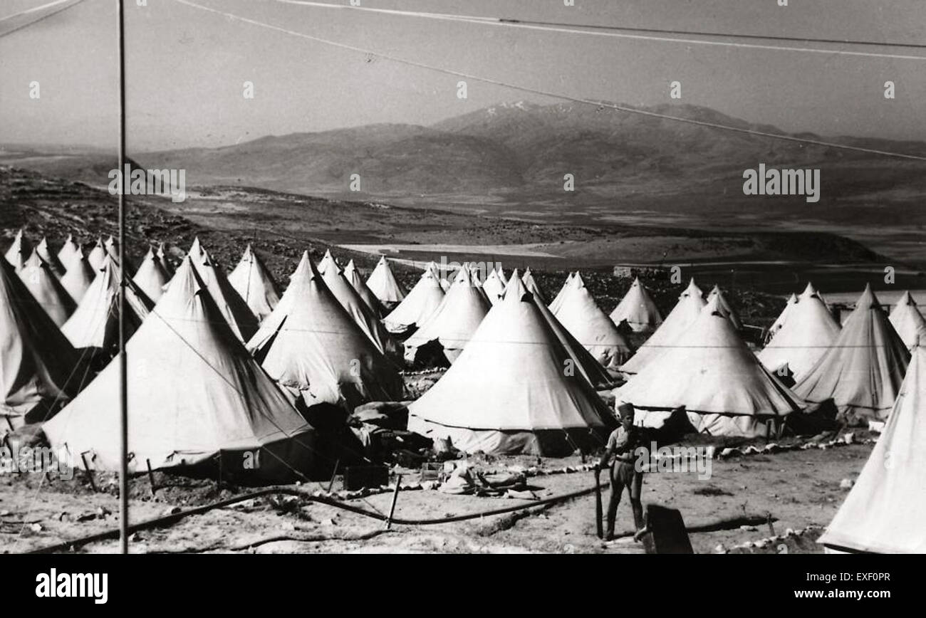 This image shows a military encampment near a barbed-wire fence, likely ...