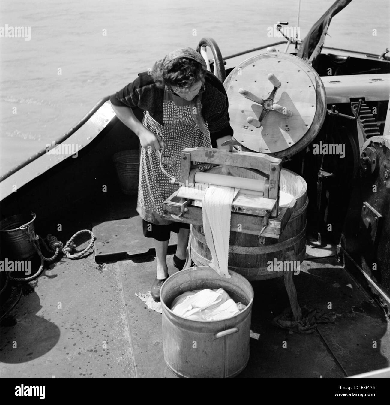 A scene depicting laundry being passed through a mangling machine ...