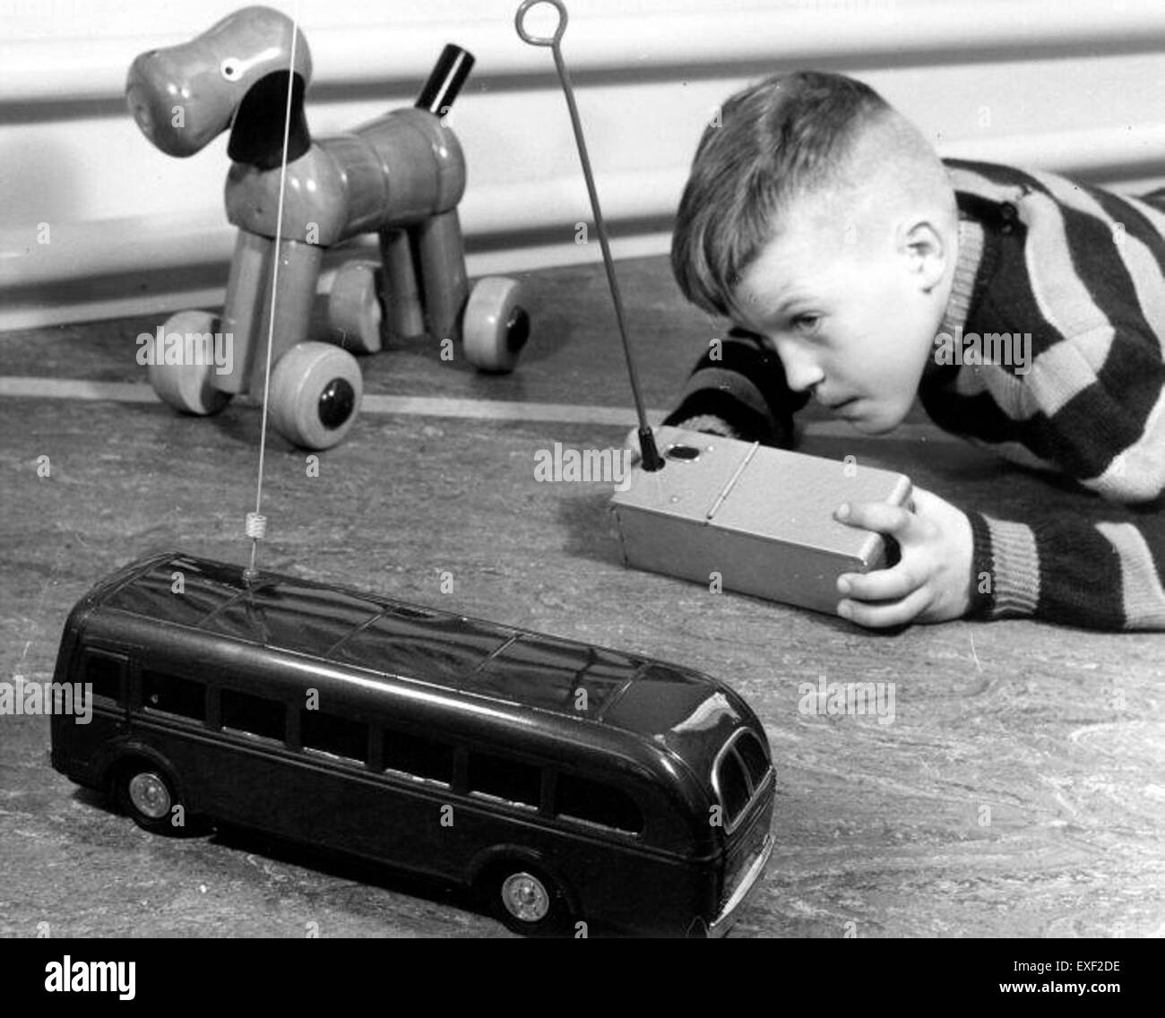 A young boy is playing with a radio-controlled toy bus, demonstrating ...