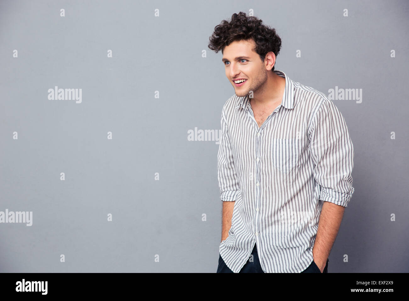 Portrait of a surprised casual man standing over gray background ...