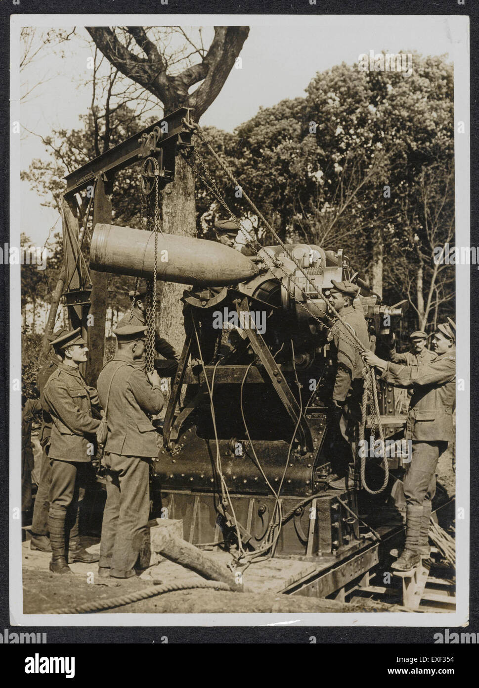 A photograph showing the process of loading a large howitzer, capturing a moment in military ...
