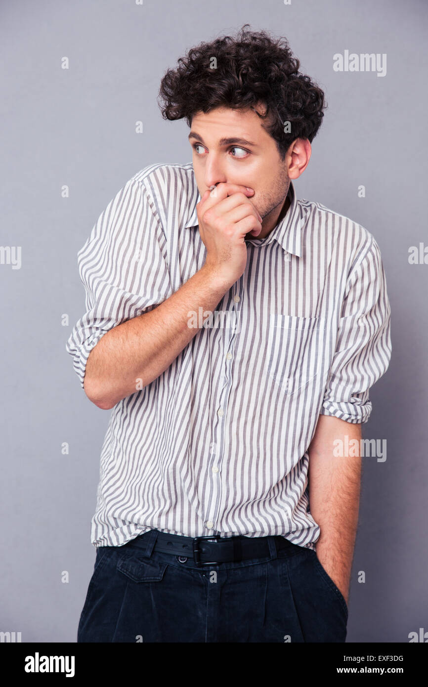 Scared young man covering his mouth over gray background Stock Photo ...