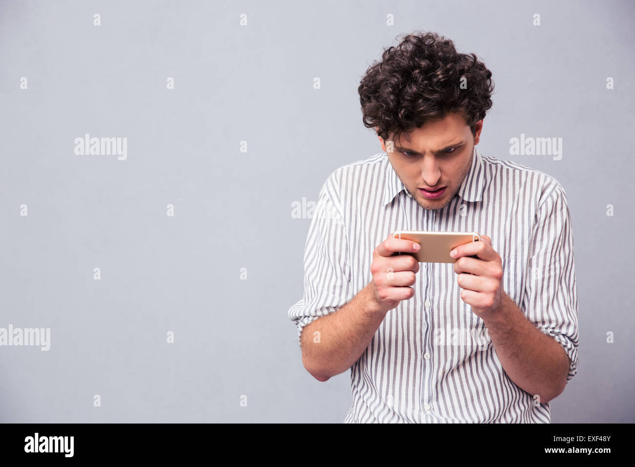 Handsome young man using smartphone over gray background Stock Photo ...