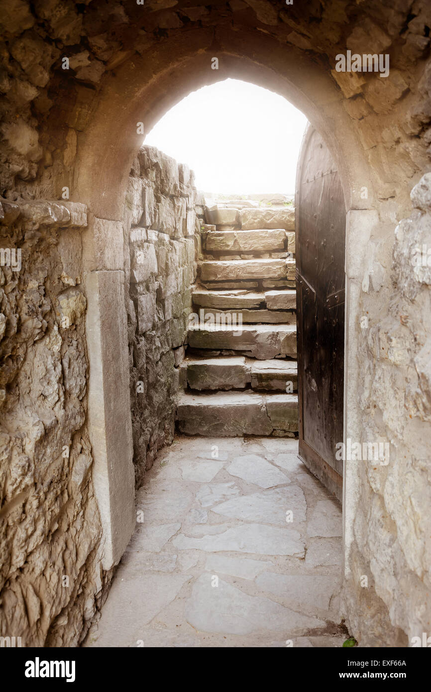 Massive stone wall with open door and rays of light behind Stock Photo ...