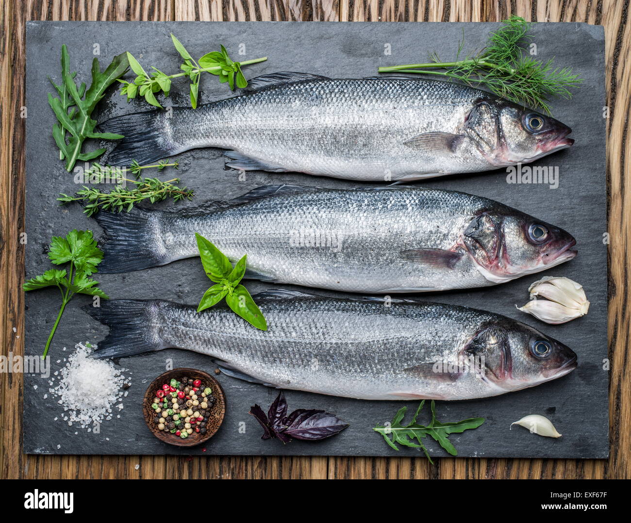Three fish - sea bass on a graphite board with spices and herbs Stock ...