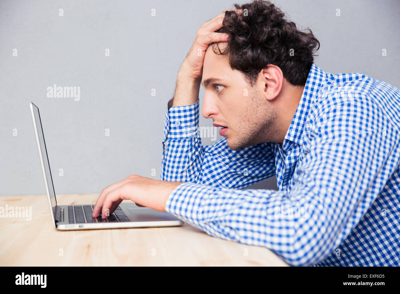 Side view portrait of a serious man sitting at the table and using ...