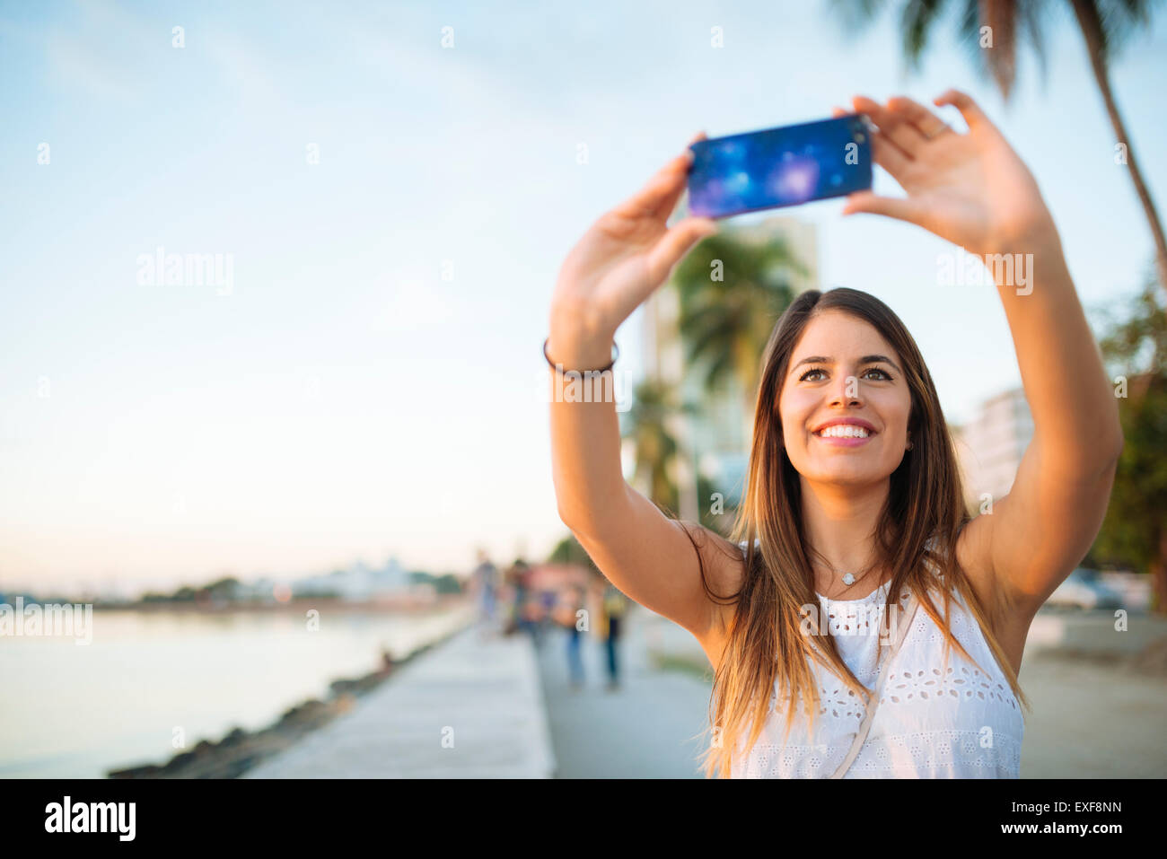 Young woman taking smartphone selfie on waterfront, Manila, Philippines ...