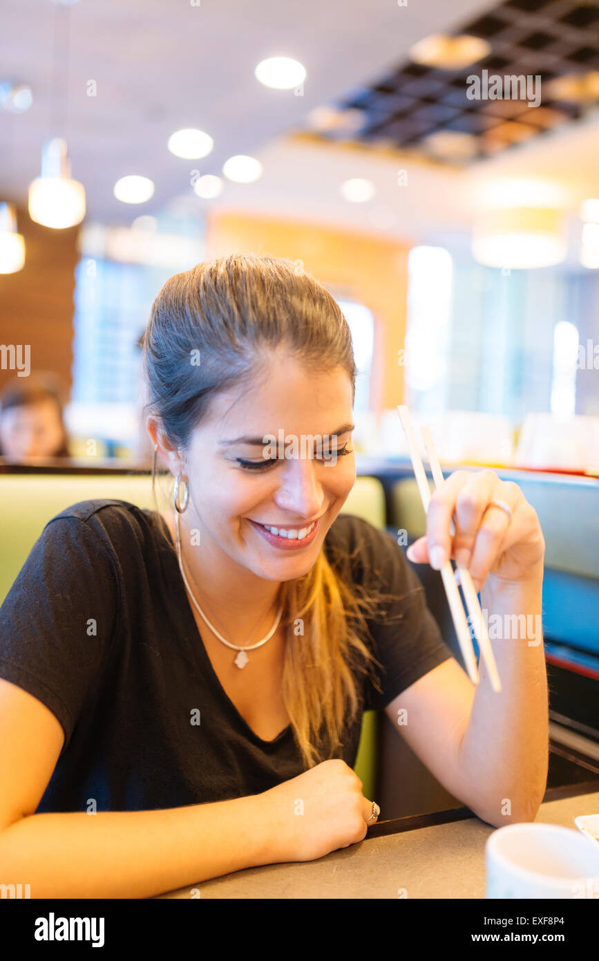 Young woman eating with chopsticks in restaurant, Manila, Philippines ...