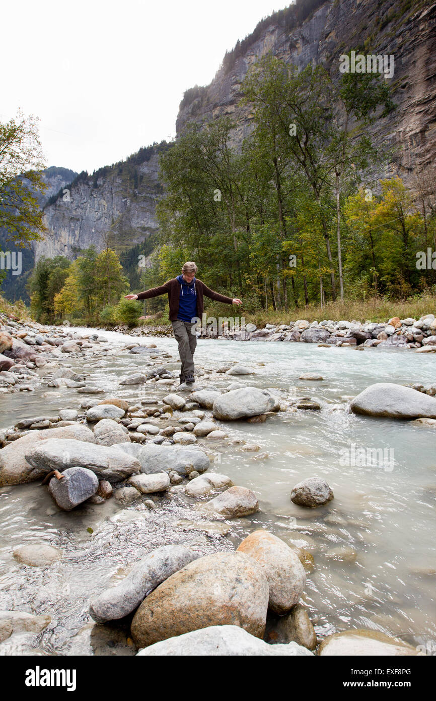 Male hiker stepping over rocks in river, Grindelwald, Switzerland Stock ...