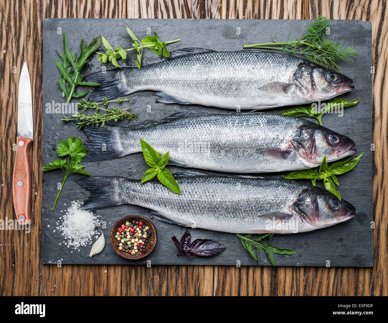 Three fish - seabass on a graphite board with spices and herbs Stock ...