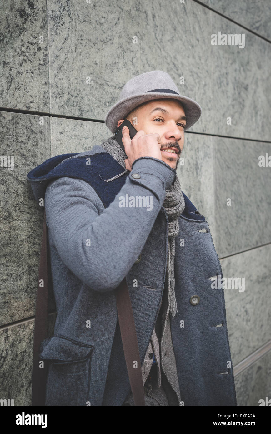 Businessman leaning against wall talking on smartphone Stock Photo - Alamy